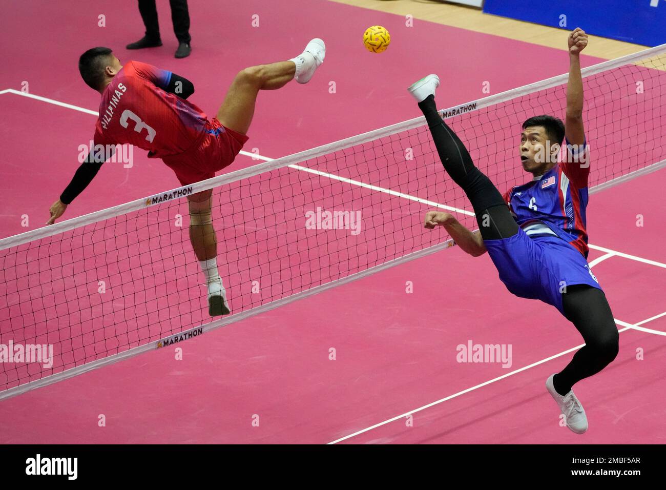 Muhammad Afifuddin Mohd Razzali of Malaysia, right, kicks a ball ...