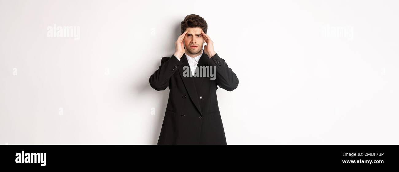 Image of businessman in black suit, touching head and looking dizzy ...