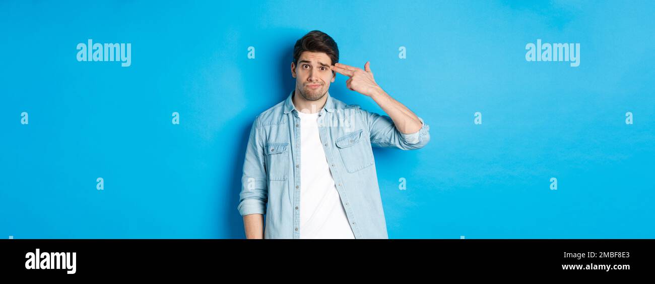 Tired and annoyed adult man making finger gun gesture near head ...