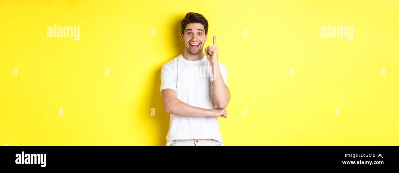 Image of attractive guy having an idea, raising finger up and ...