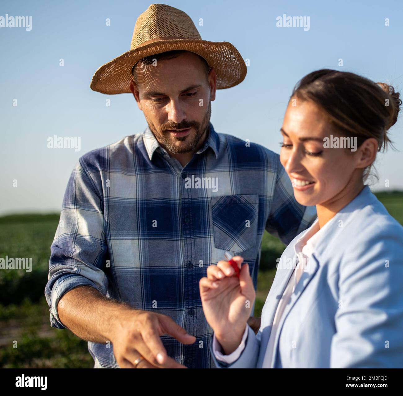 Pretty business woman and handsome farmer signing documents on field in ...