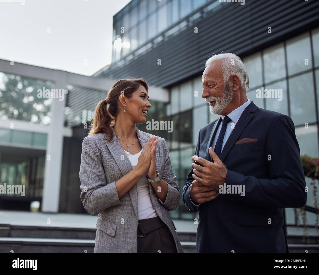 Senior businessman and young woman talking in hurry in front of office building Stock Photo - Alamy