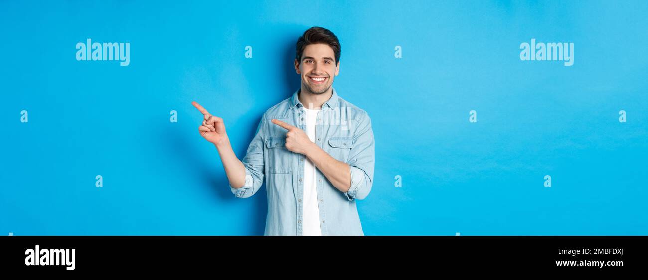Portrait of attractive adult man smiling, pointing fingers right at ...