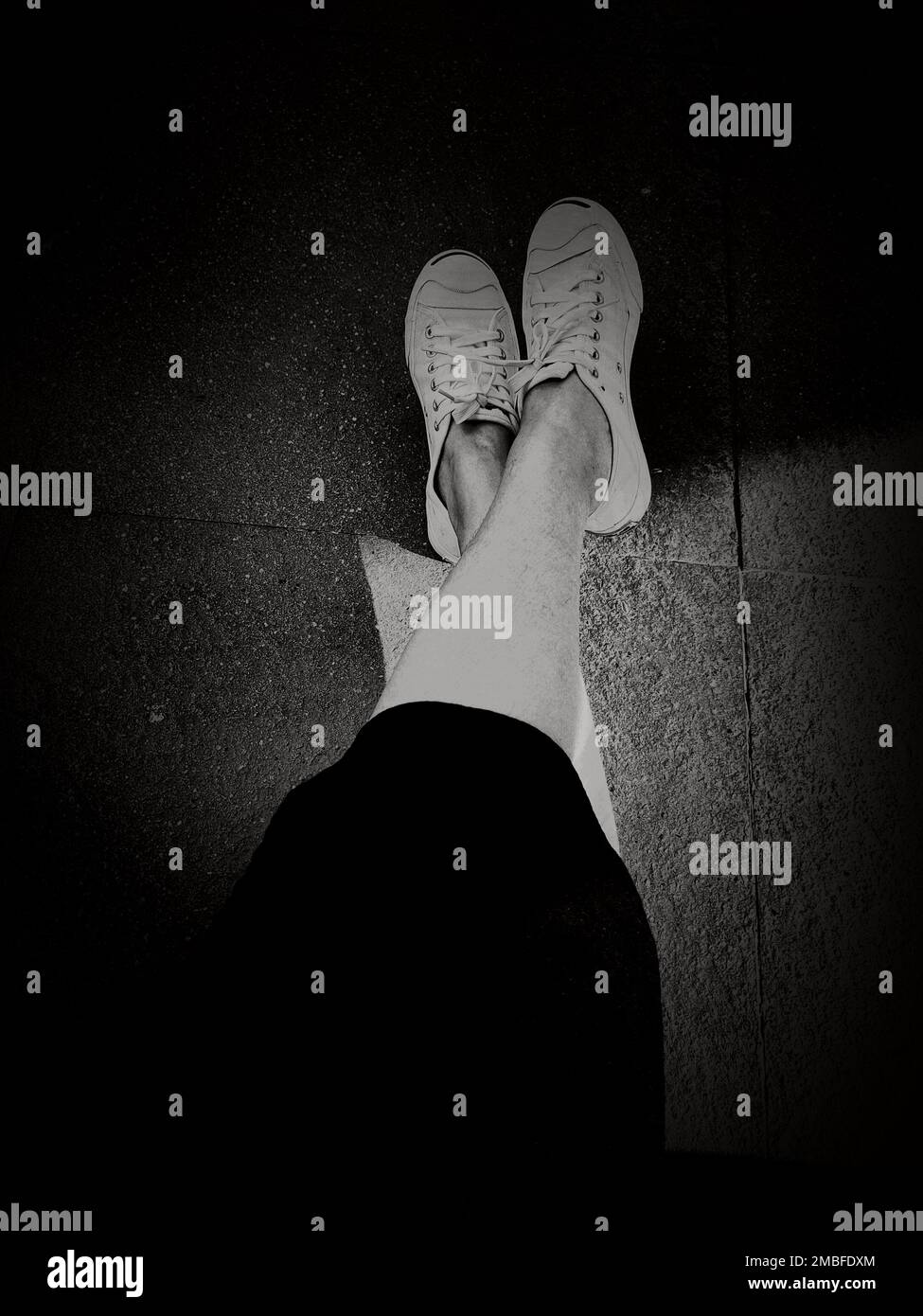 A grayscale of woman legs in sneakers Stock Photo - Alamy