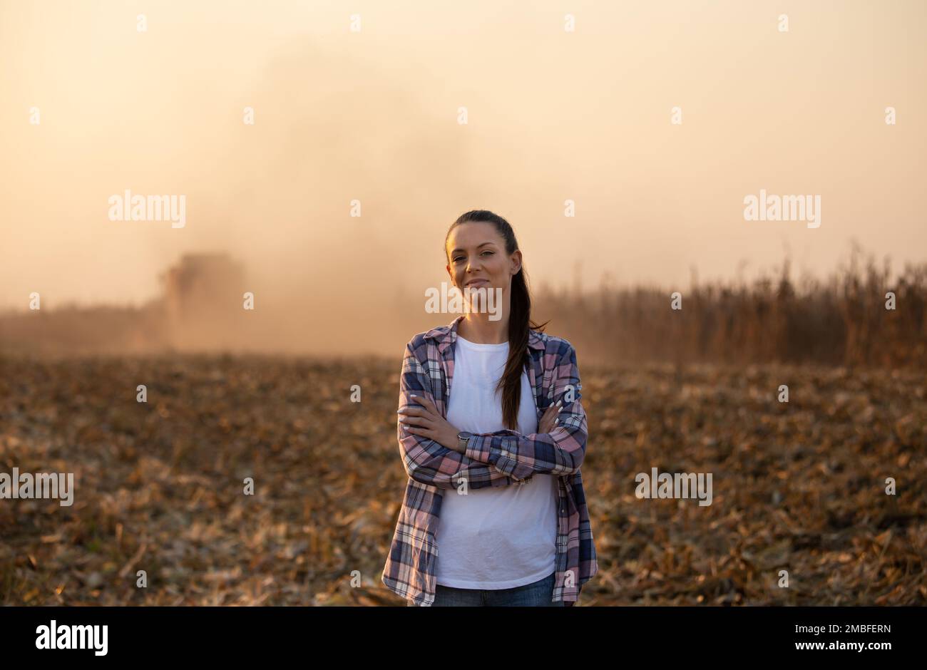 Portrait of farmer woman standing in corn field with crossed arms while ...