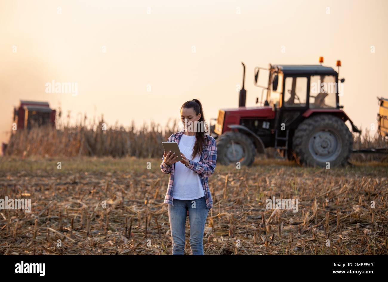 Portrait of farmer woman with tablet standing in corn field while ...