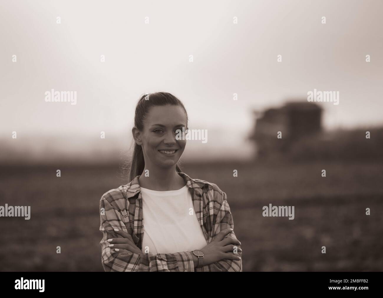 Portrait of pretty farmer woman standing in corn field with crossed ...