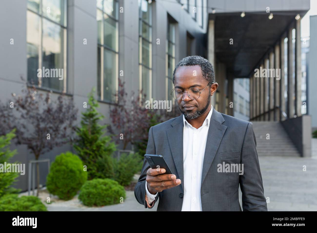 Serious afro american boss in business suit walking outside office ...