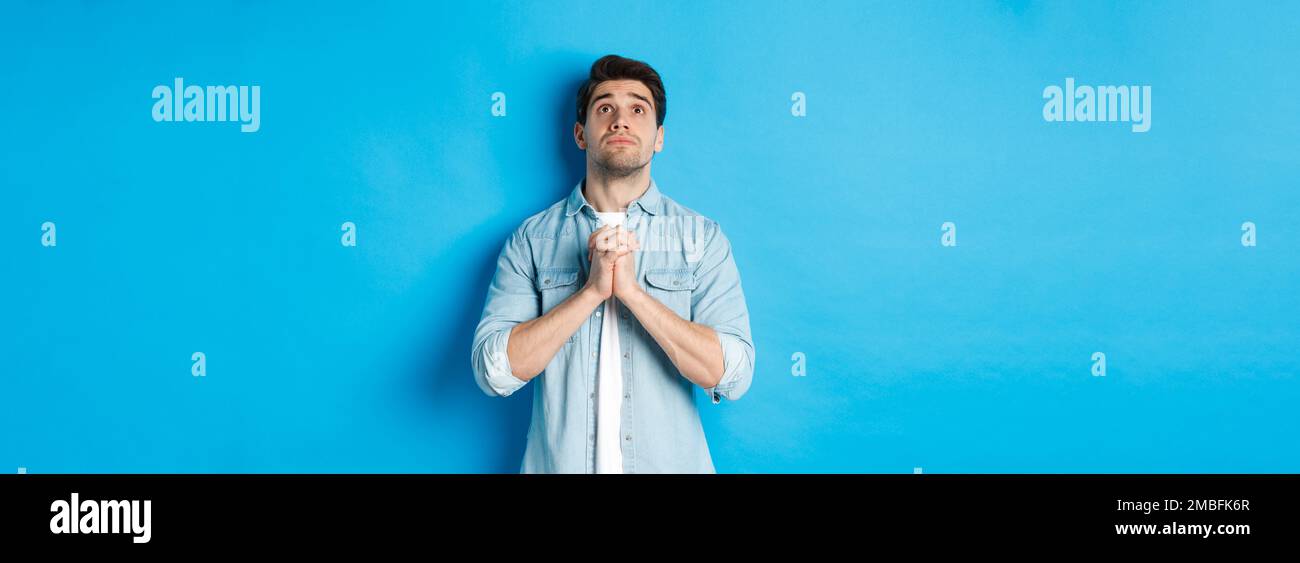 Hopeful young man looking up and praying God, begging for help ...