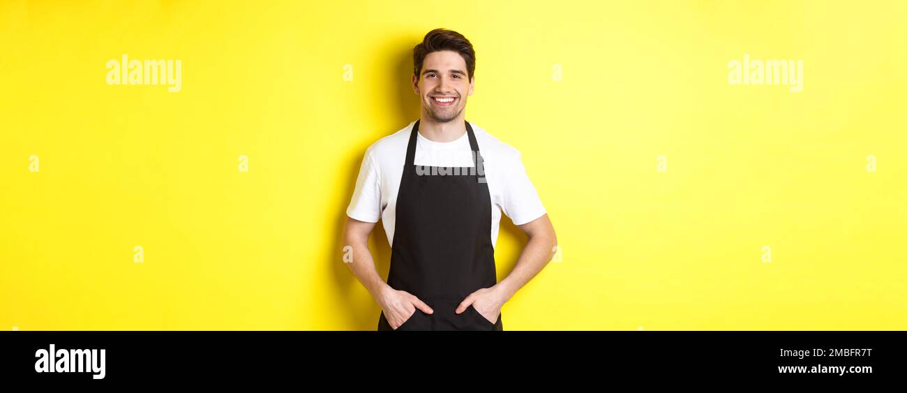 Happy barista in black apron looking at camera. Coffee shop owner ...