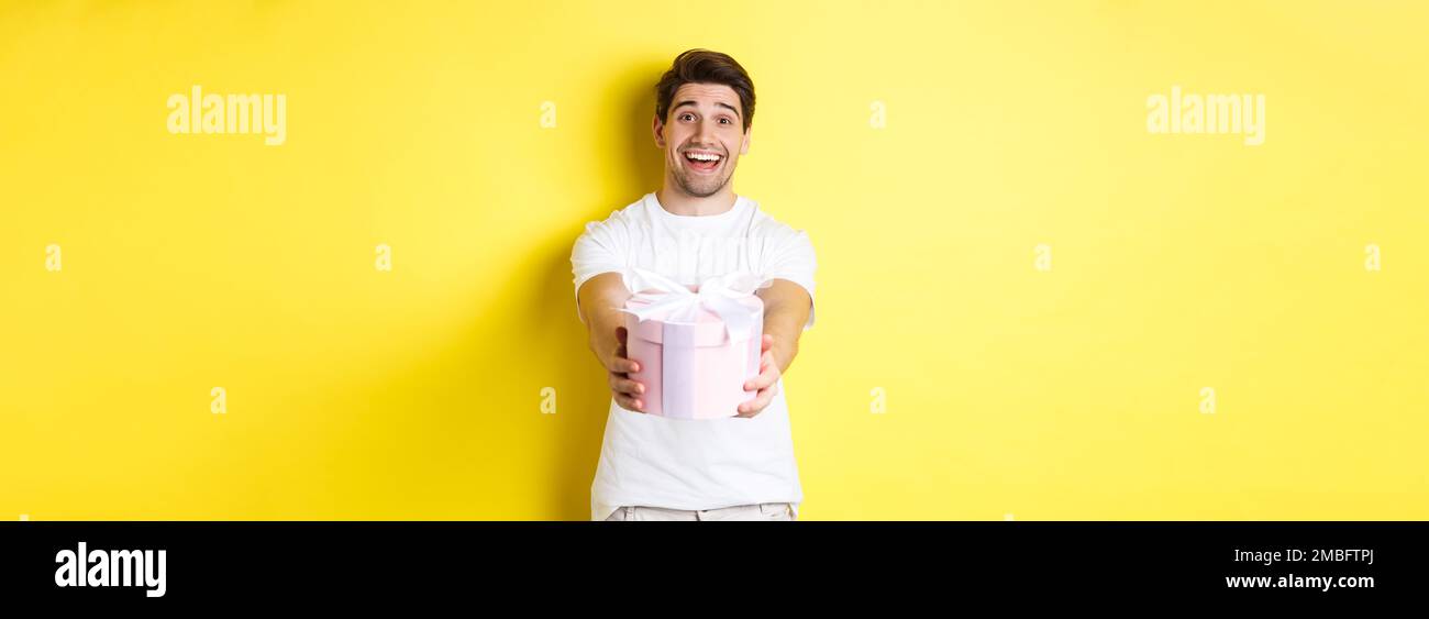 Concept of holidays and celebration. Smiling man giving you gift ...