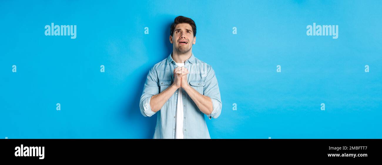 Desperate man begging and crying for help, pleading to god, looking up ...