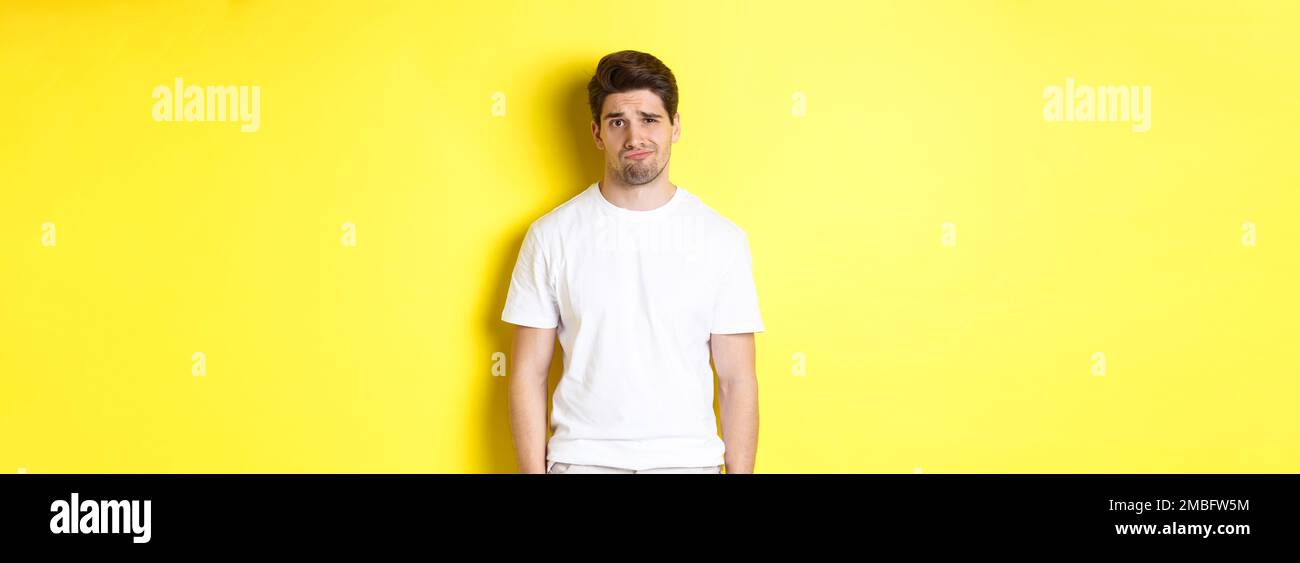 Disappointed guy looking upset, sulking and frowning, standing ...