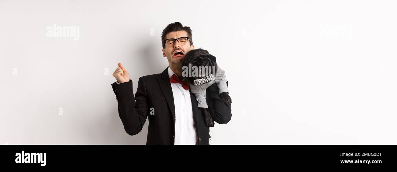 Sad man in suit, holding cute small dog on shoulder and crying with ...