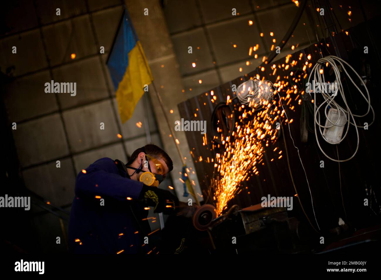 A volunteer shapes metal plates with an angle grinder at a facility ...