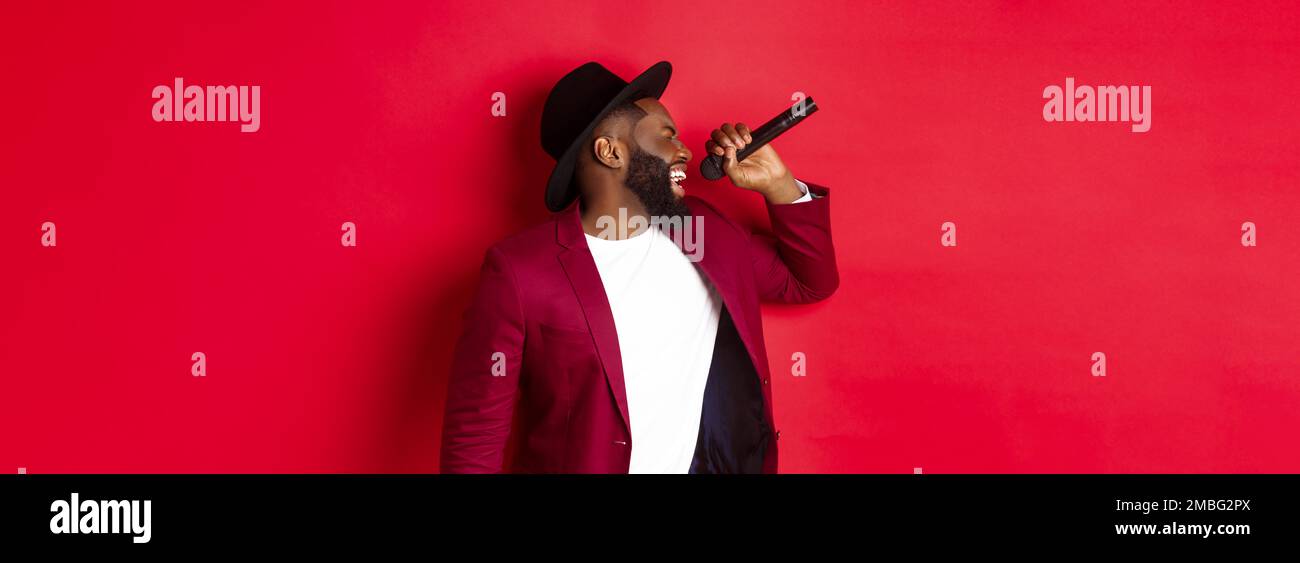 Passionate black male singer performing against red background, singing ...