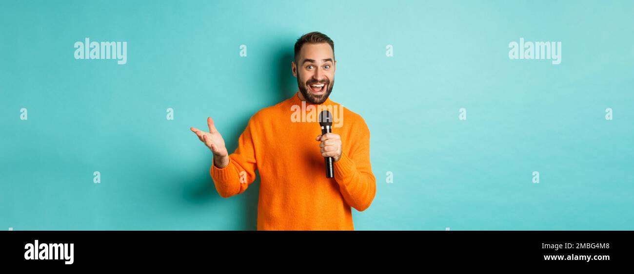 Handsome adult man perform song, singing into microphone, standing ...