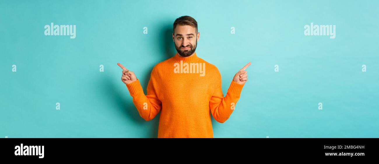 Doubtful and indecisive man pointing fingers sideways, showing ...