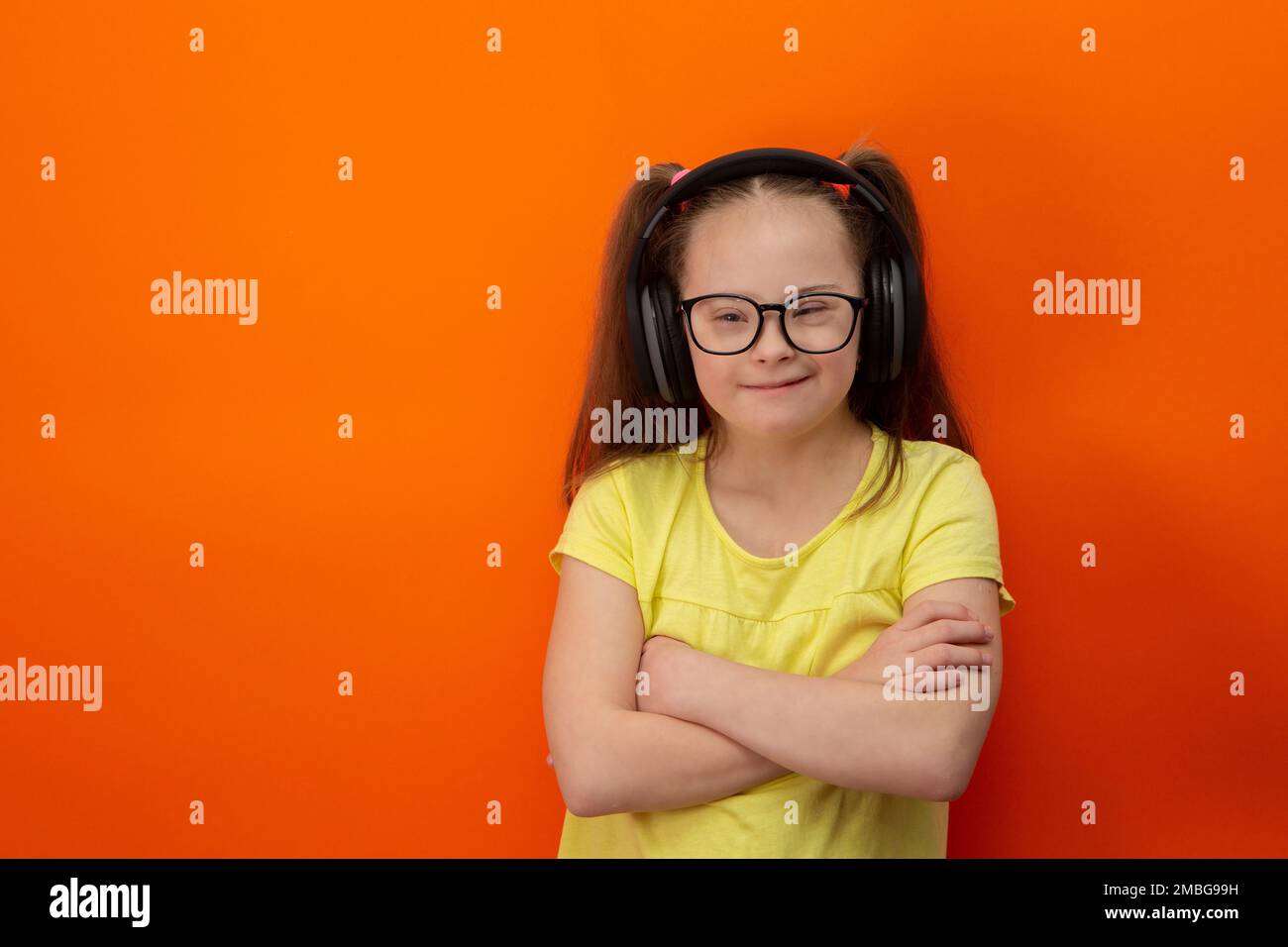 Girl with Down syndrome listens to music. Orange background Stock Photo - Alamy