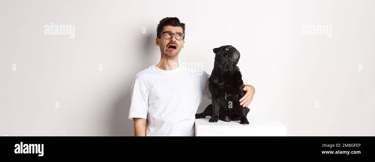 Whining man looking sad while pug staring intrigued at upper left ...