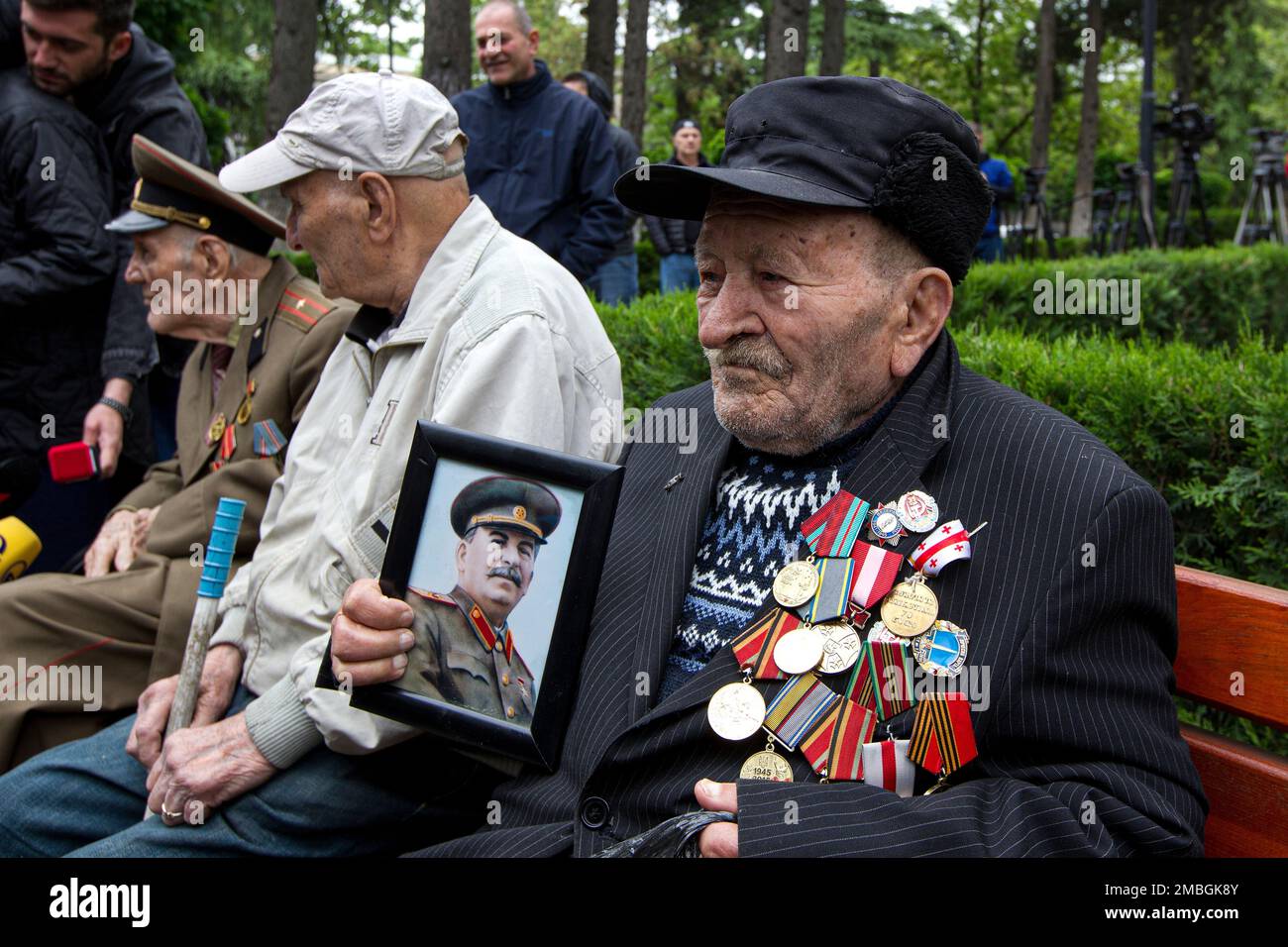 A WWII veteran holds a portrait of Josef Stalin as he and other ...