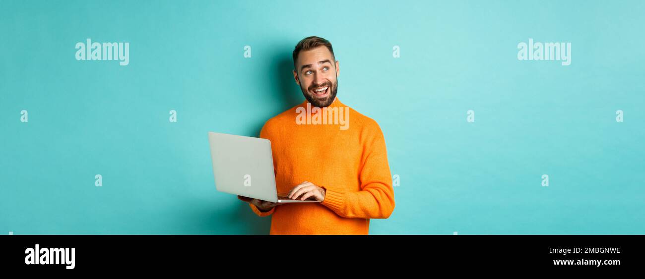 Handsome man doing online shopping, looking up thoughtful while using ...