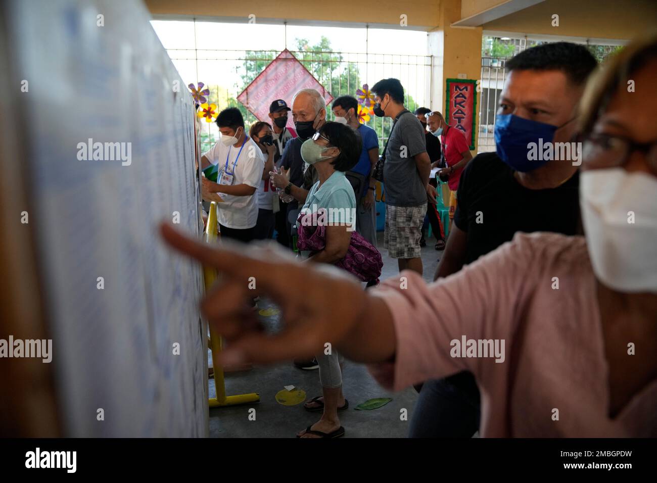 Residents look for their precincts on a list posted at a polling center ...