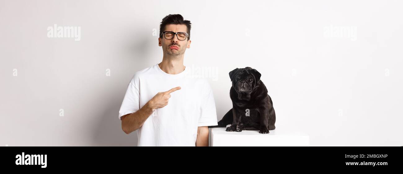 Sad and gloomy pet owner pointing at his black pug dog and sobbing ...