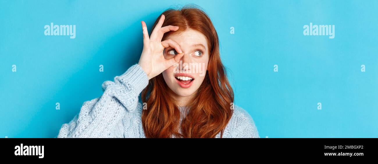 Headshot of pretty redhead girl in sweater, looking left at promo with ...