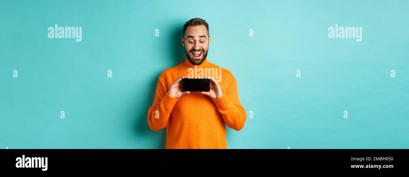 Excited guy demonstrating online store, showing mobile screen and ...