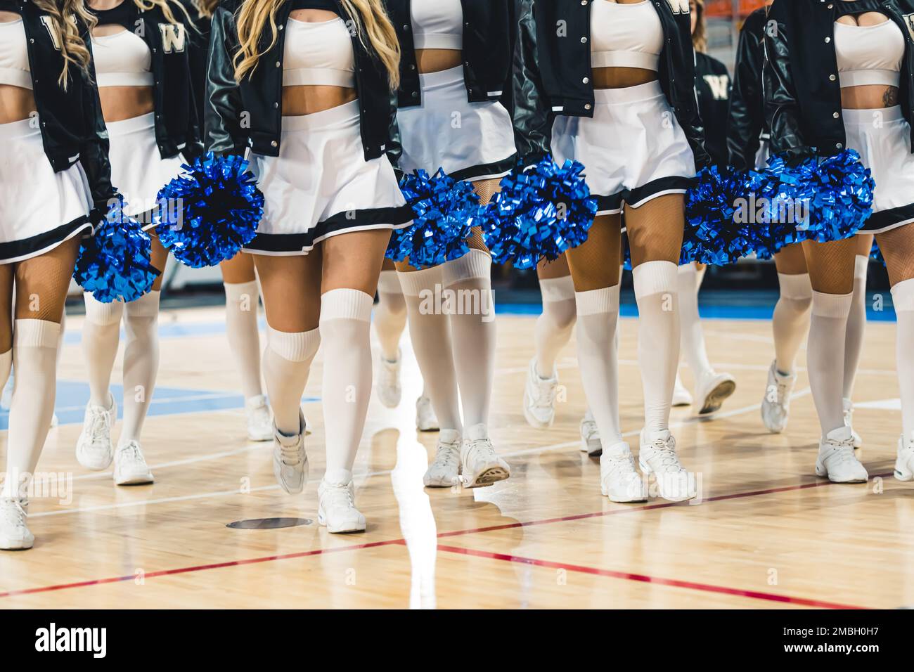 Medium shot of cheerleaders walking on basketball court and holding ...