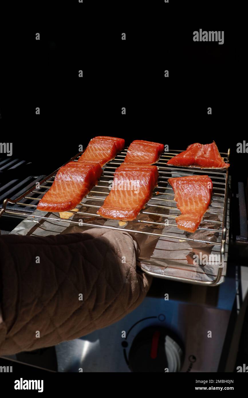 close up of man taking grilled salmon steaks out from grill Stock Photo ...