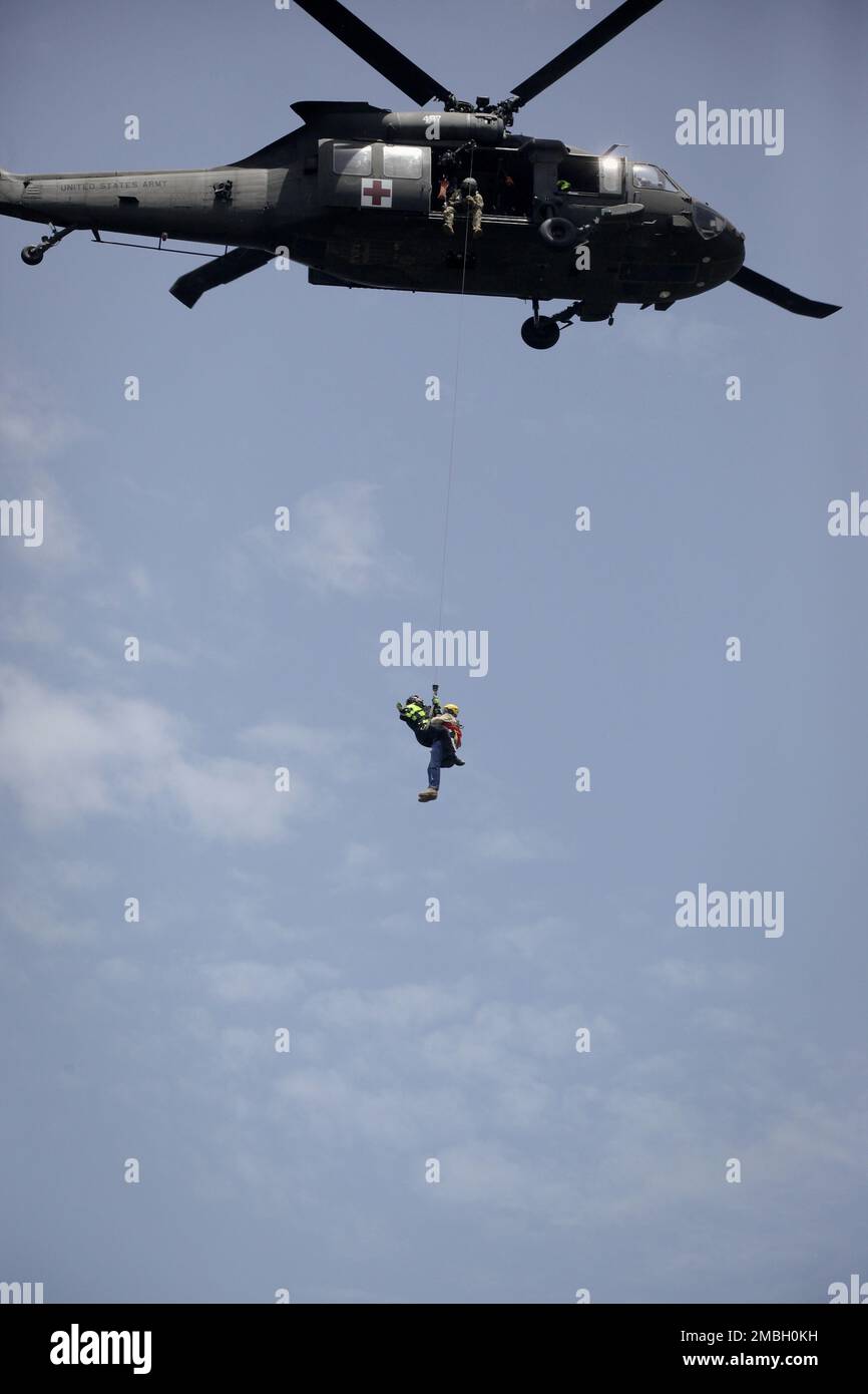 A HH-60M MEDEVAC Black Hawk hovers as a hoist team conducts personnel ...