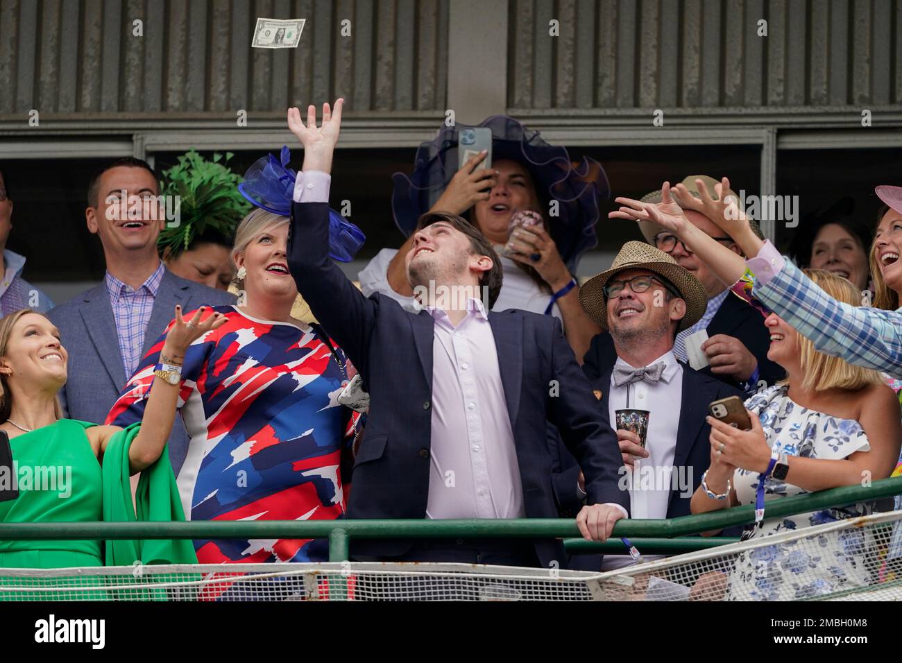 Spectators reach for a dollar thrown from a balcony above them before ...