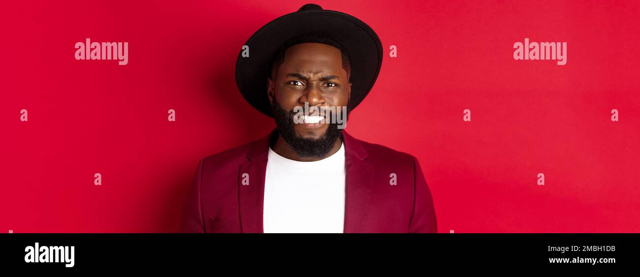 Close-up of Black man feeling uncomfortable, grimacing as watching ...