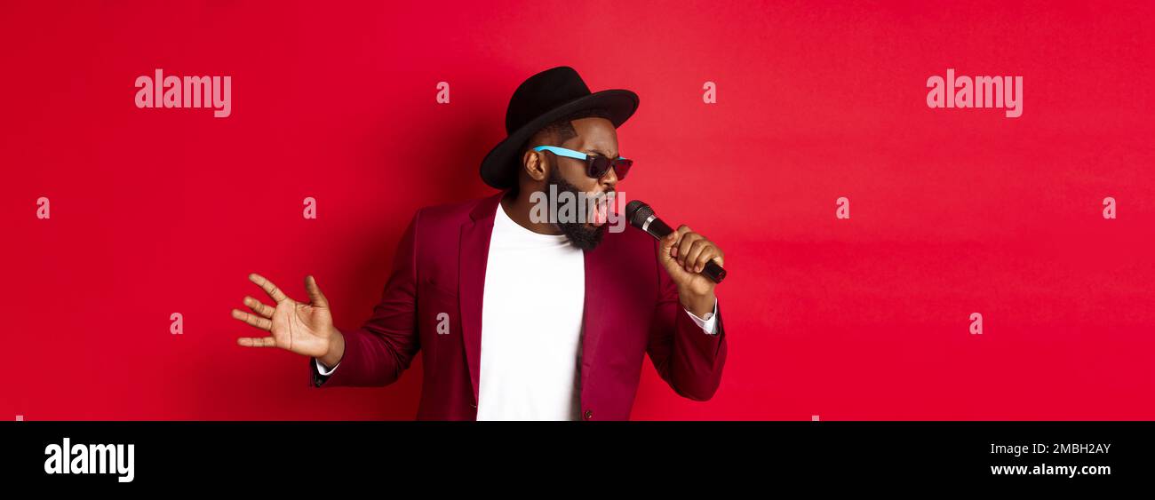 Passionate black male singer performing against red background, singing ...