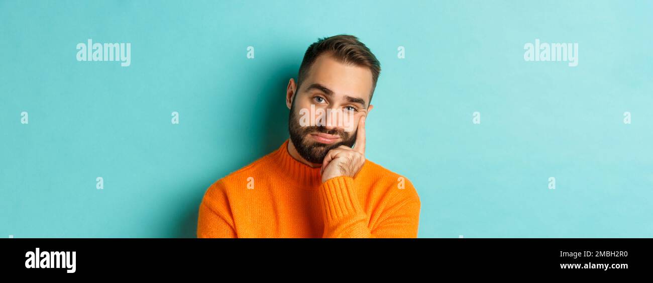 Close-up of unamused sad man looking at camera, pouting and leaning ...