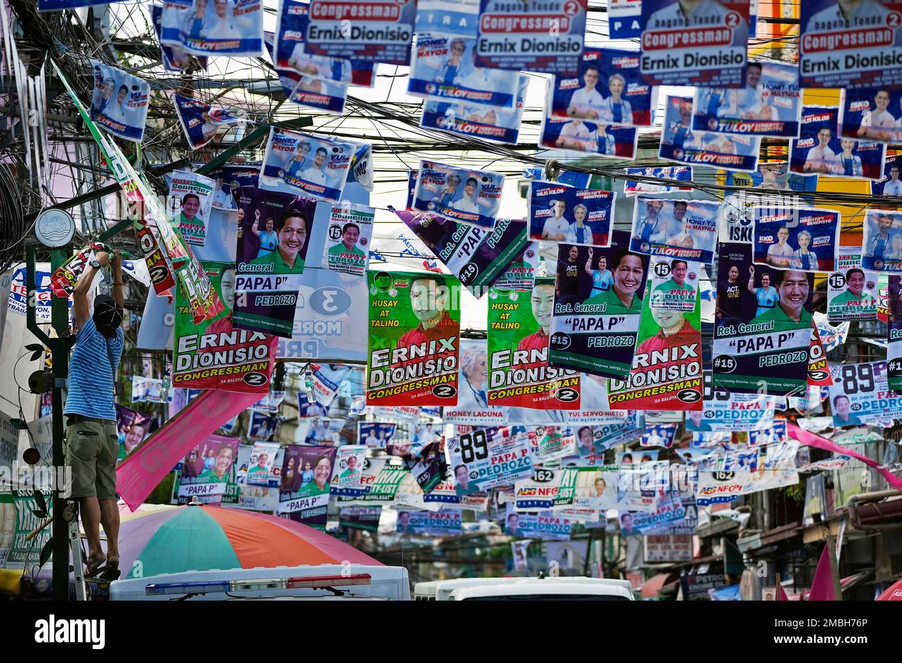 A man hangs election campaign posters near a polling center in Manila ...