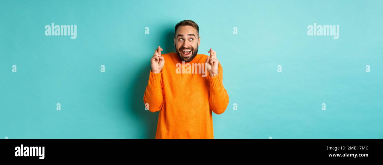 Excited man expecting something with anticipation, hold fingers crossed ...