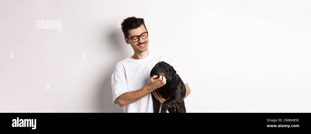 Happy dog owner scratching cute black pug face and smiling, pet his ...