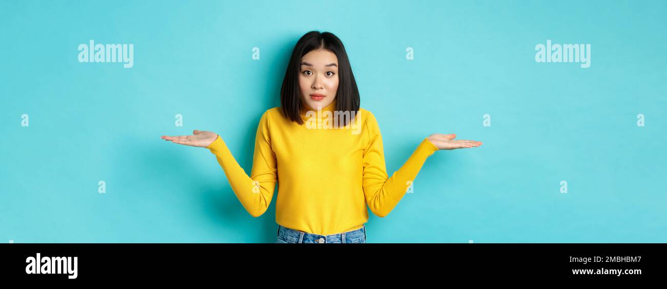 Image of indecisive asian woman shrugging shoulders, spread hands ...