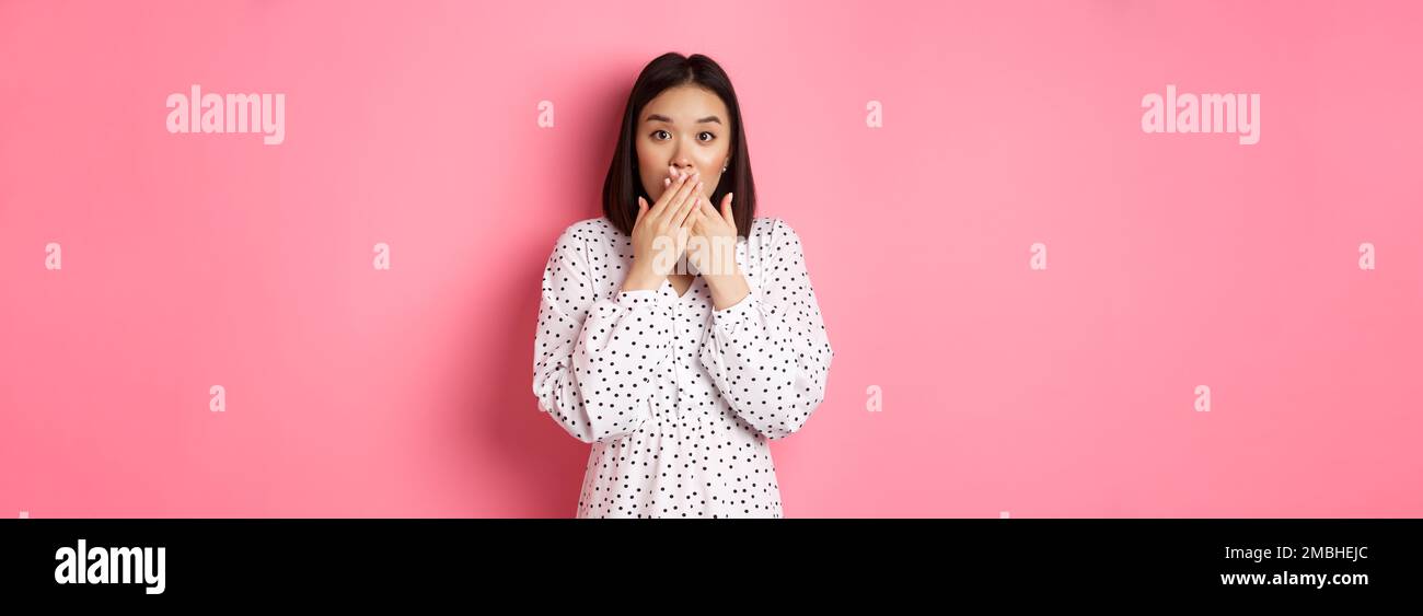 Image of surprised asian female model gasping, cover mouth and looking ...