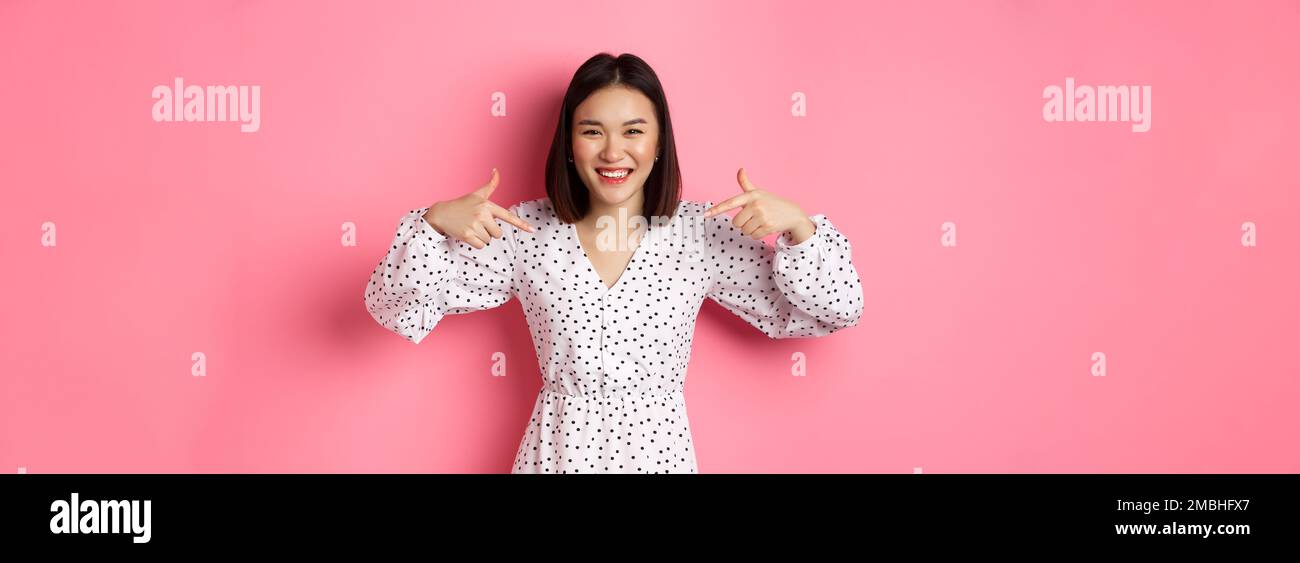 Beautiful korean woman pointing fingers at your logo and smiling ...