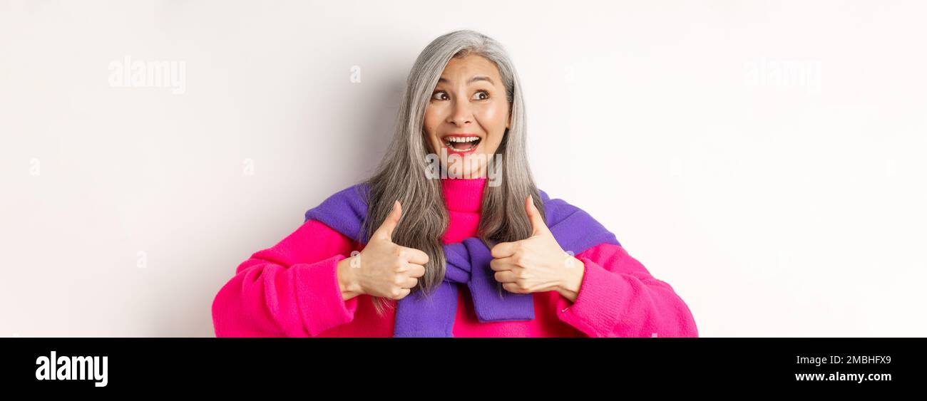 Excited and amazed asian elderly woman showing thumbs-up in approval ...