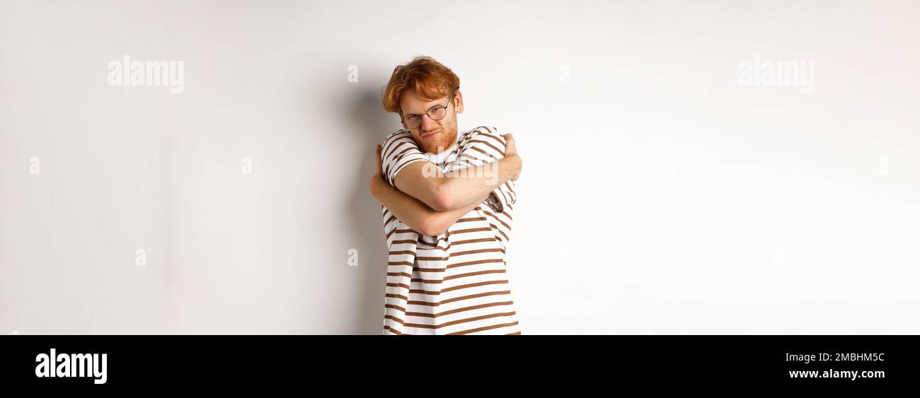 Reluctant young man with messy red hair unwilling do something, hugging ...