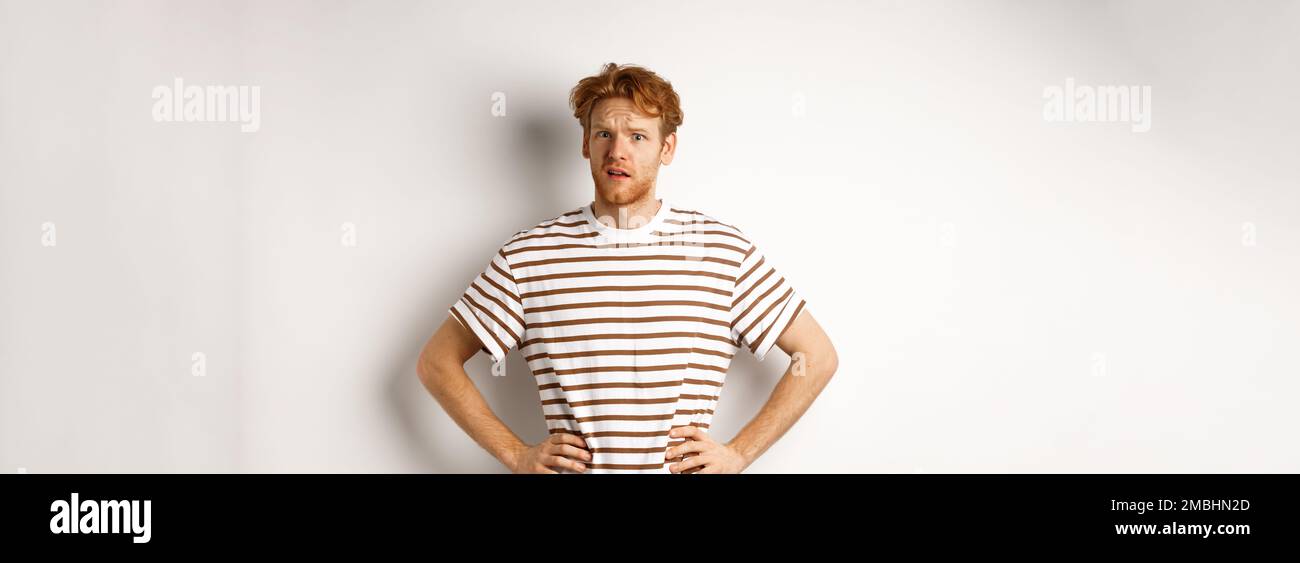 Confused and offended man with ginger curly hair staring at camera ...