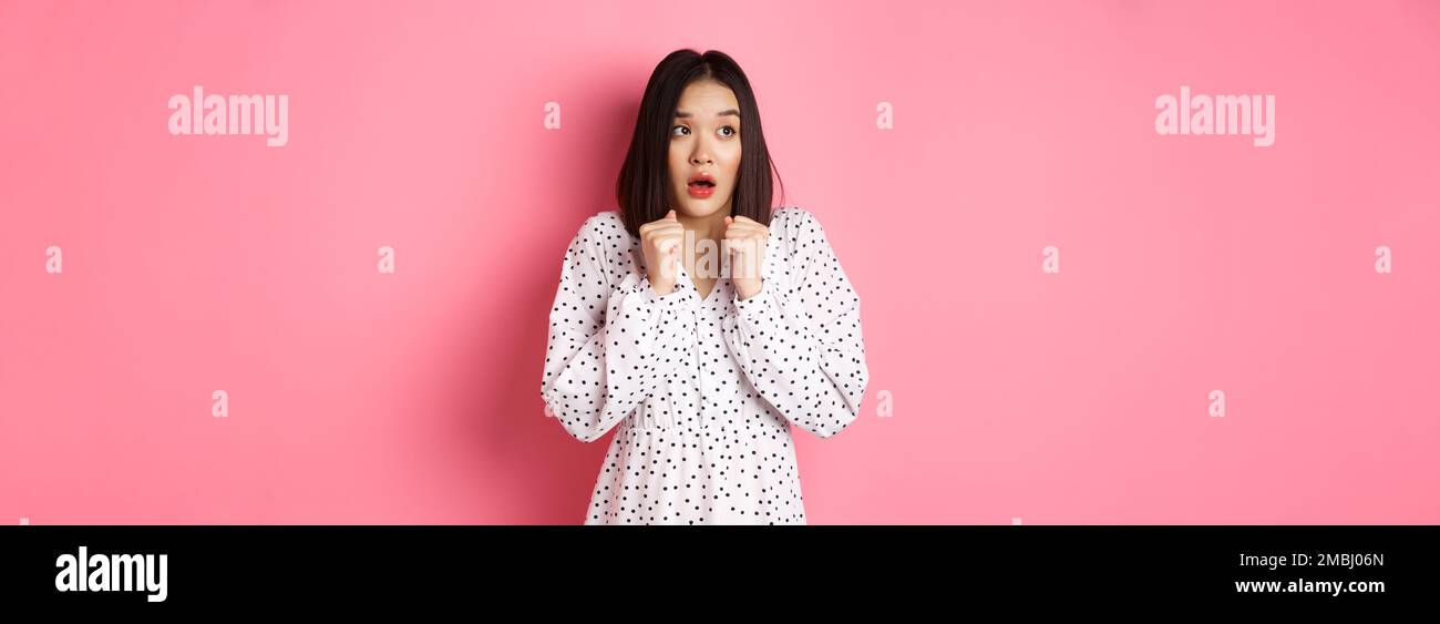 Scared and timid asian girl trembling from fear, staring left and ...