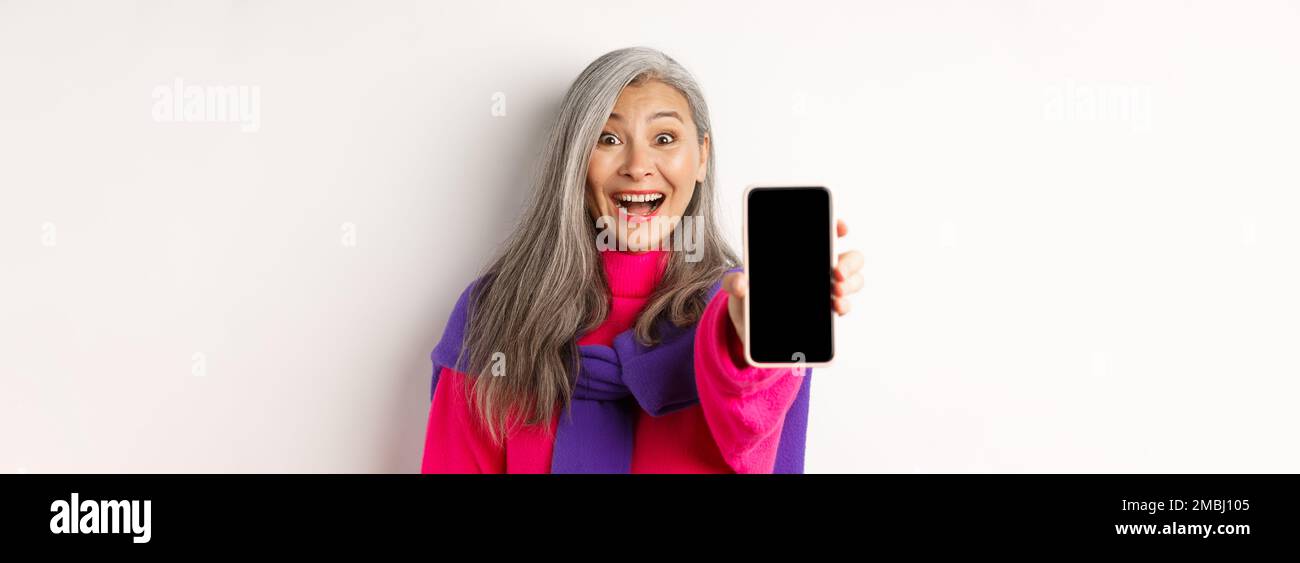 Online shopping. Close up of stylish asian senior woman extending hand ...