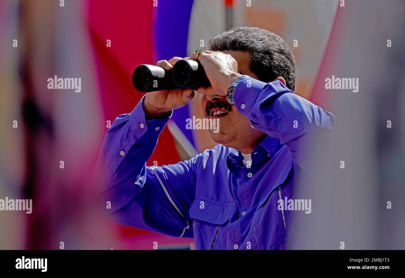 Venezuela's President Nicolas Maduro looks through a pair of binoculars ...
