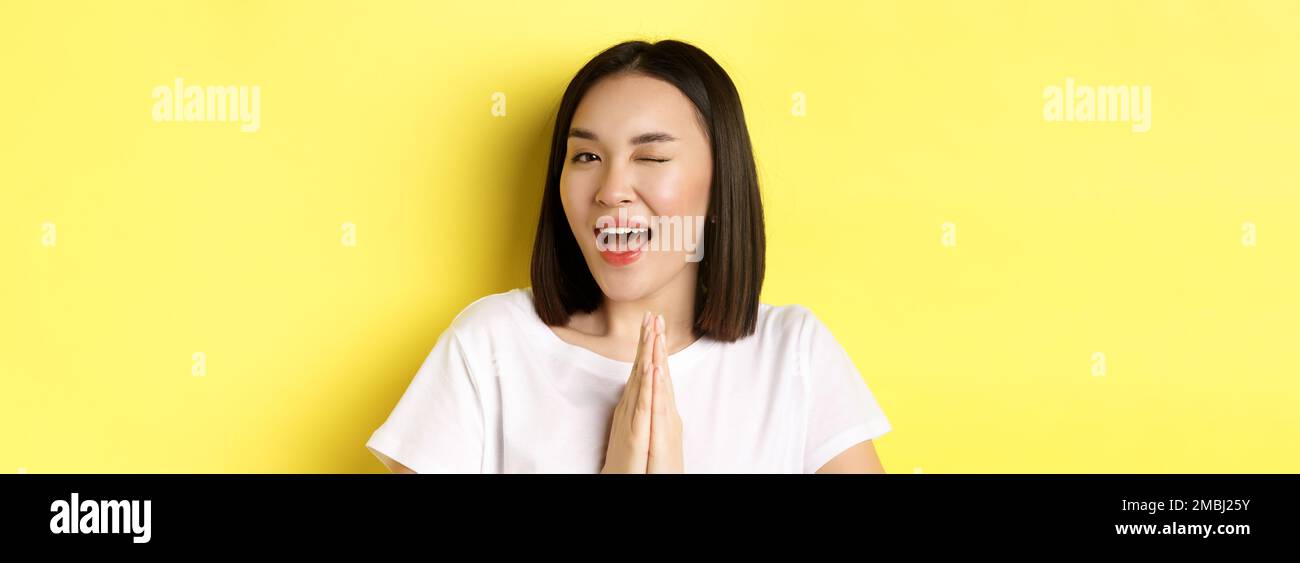 Close of cheeky young asian woman holding hands in namaste, thank you ...